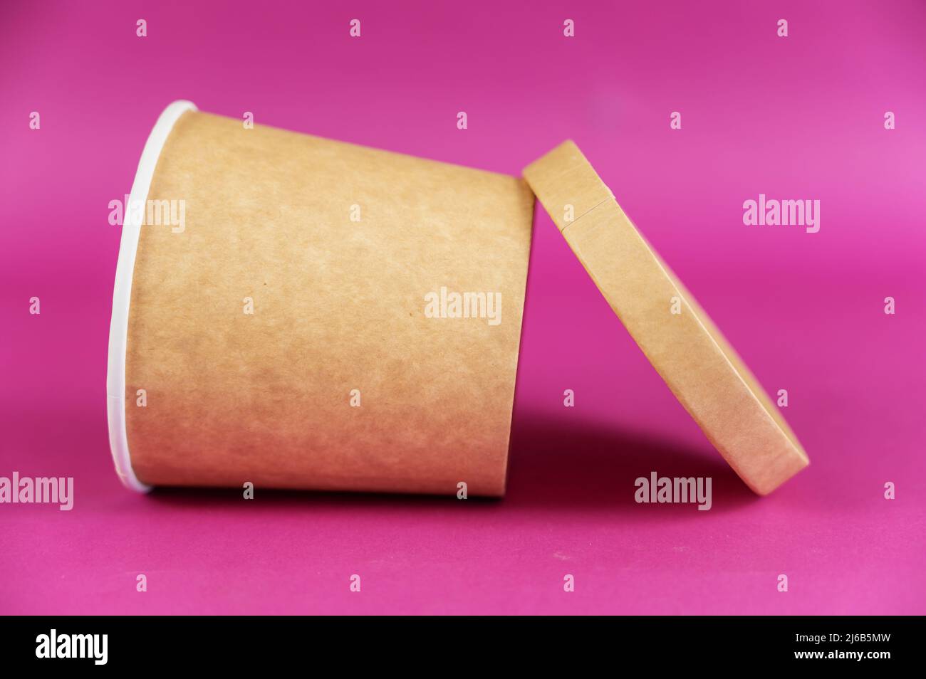 Empty cylindrical paper container with lid opposite-colored background ...