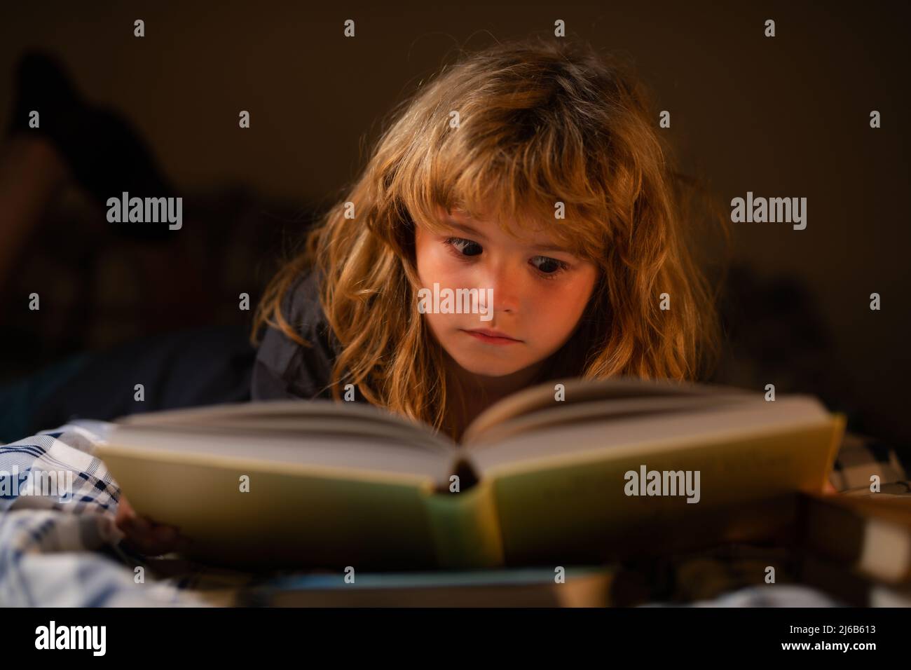Child reading a magic book in bed. Kid boy read books at home ...