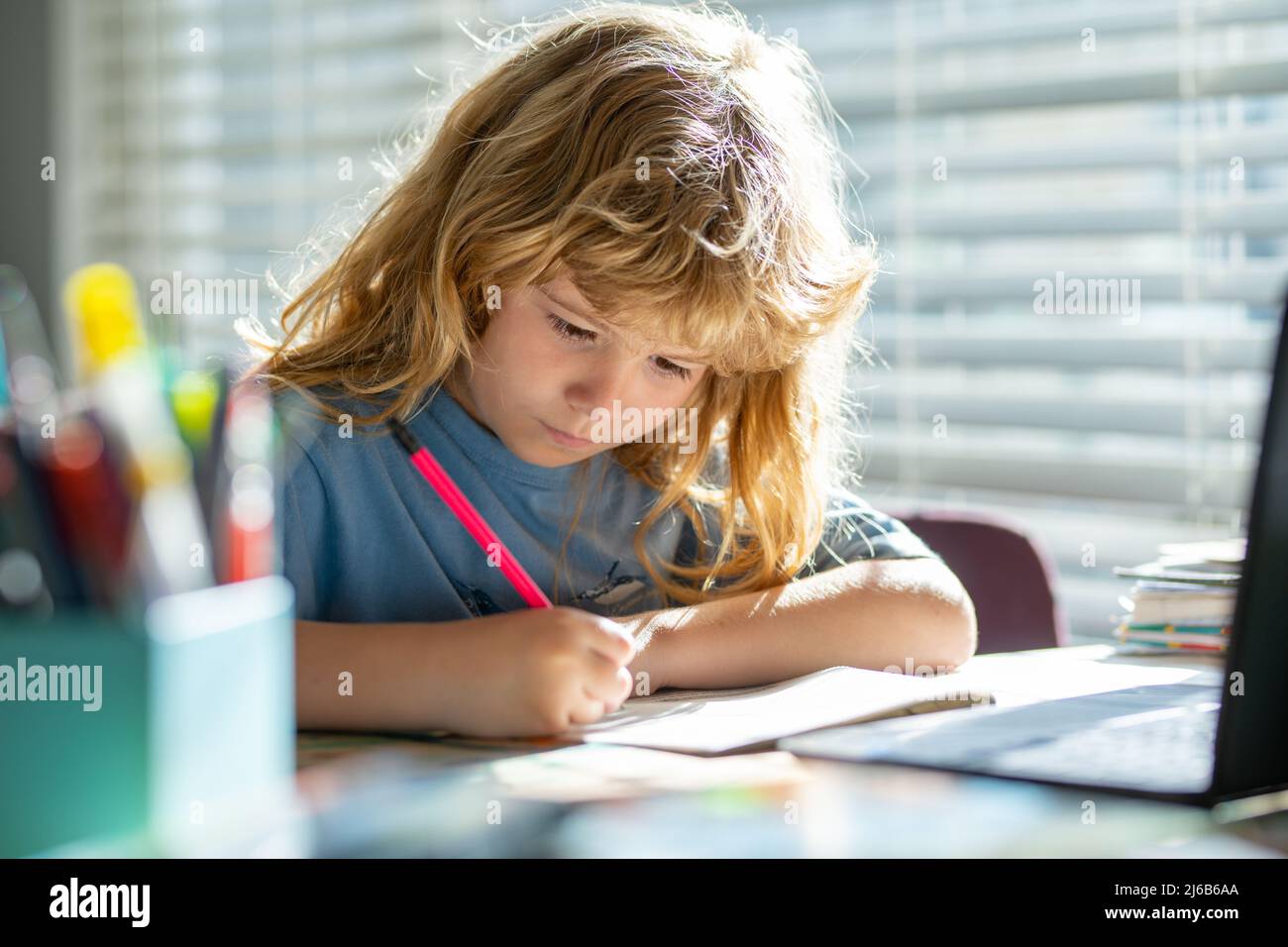 Child writing at school. Portrait of school kid boy siting on table ...