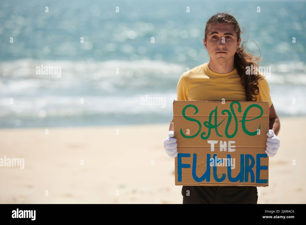 Environmental activist standing on beach with save the future placard ...