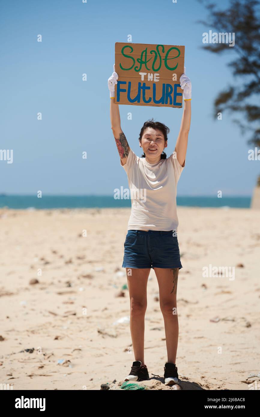 Happy excited young woman showing save the future placard when standing ...