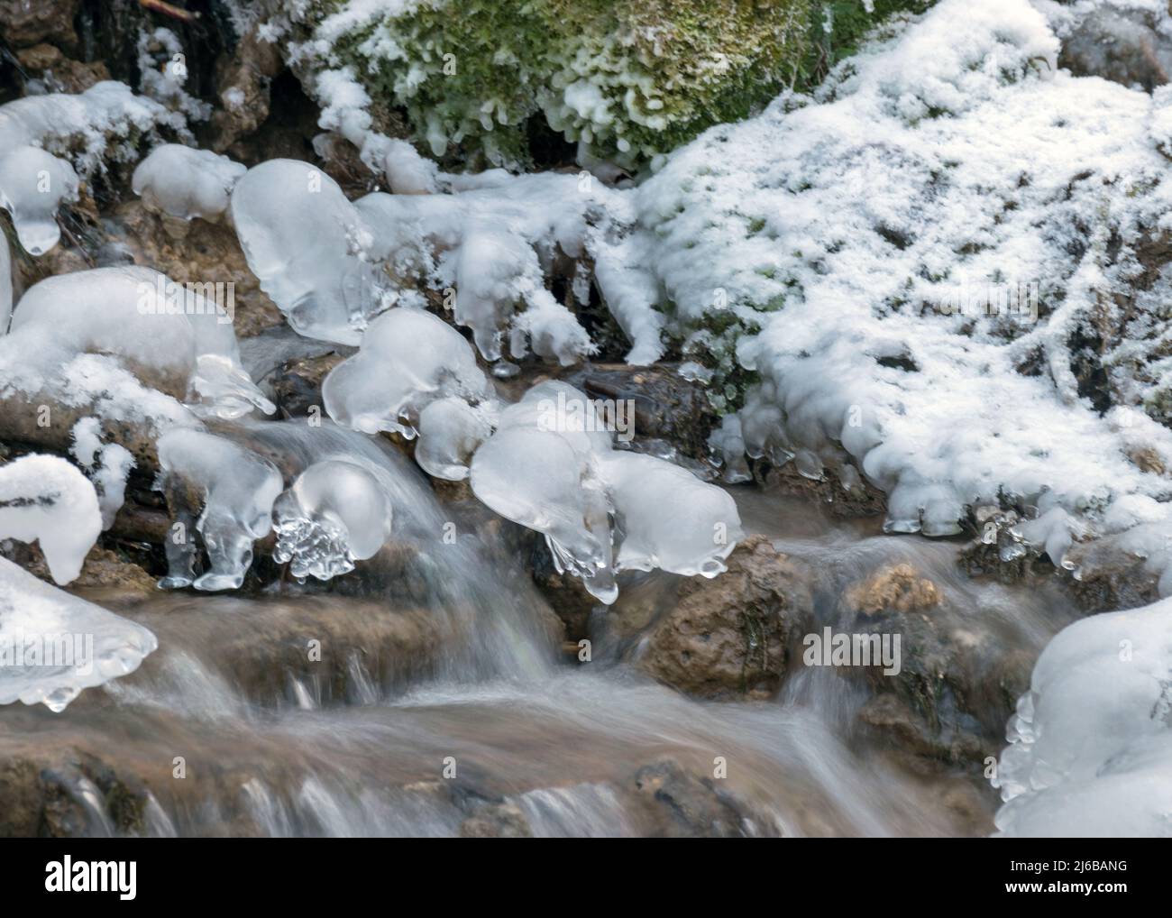 frozen fast flowing spring water, icy rocks and water stream, frosty ...