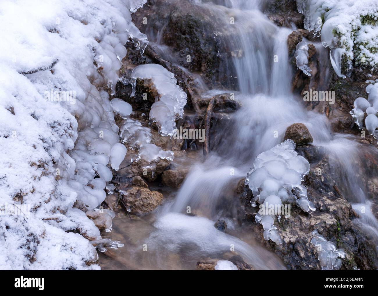 frozen fast flowing spring water, icy rocks and water stream, frosty ...