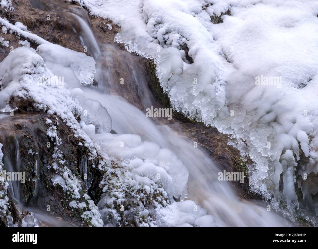 frozen fast flowing spring water, icy rocks and water stream, frosty ...