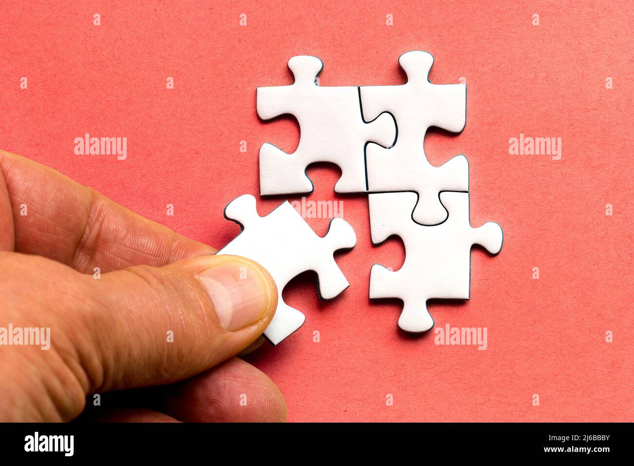 a human hand laying a piece of a jig saw puzzle Stock Photo - Alamy