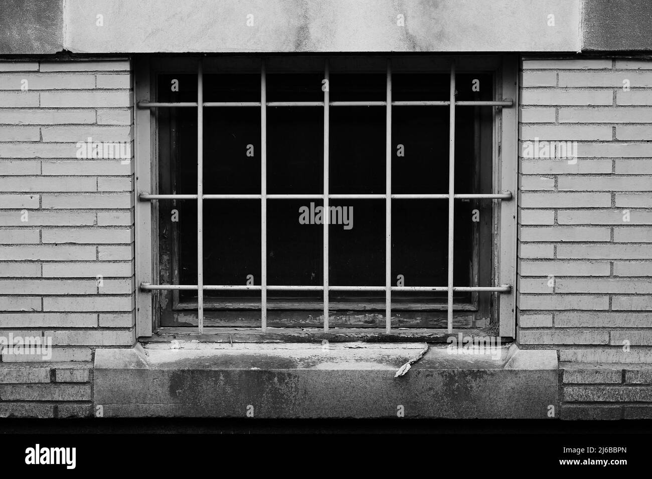 An inner city basement window with an iron security grill in black and ...