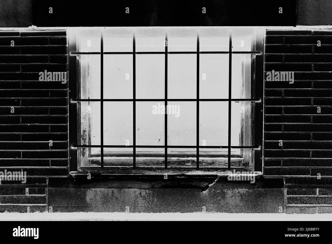 An inner city basement window with an iron security grill in black and ...