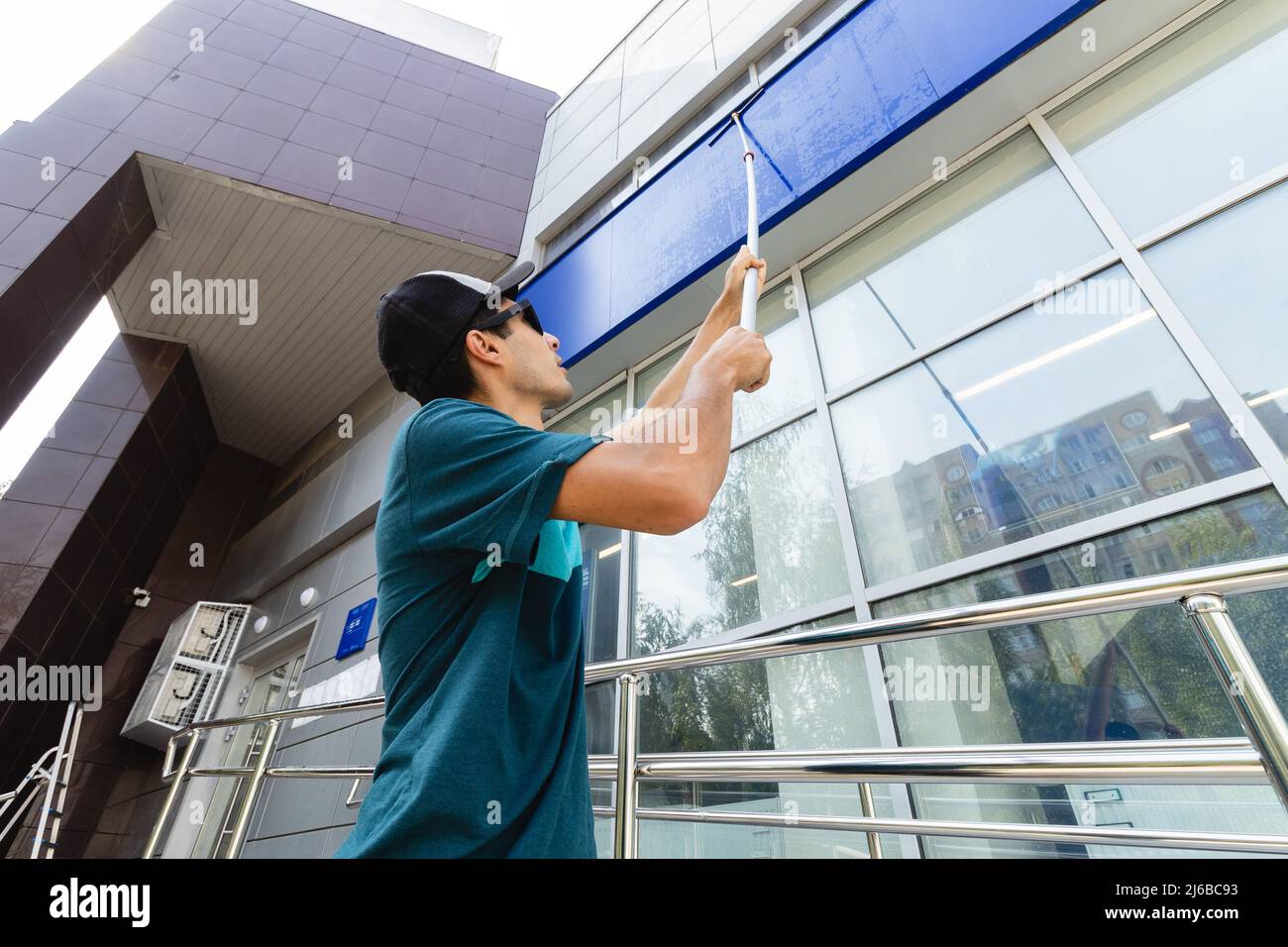 An employee of a professional cleaning service in overalls washes the ...
