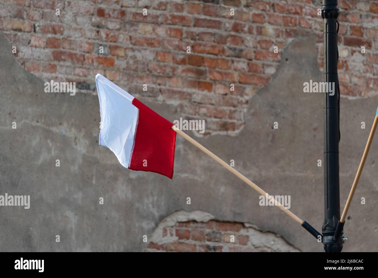 A small Polish flag on a blurry background of bricks with peeling ...