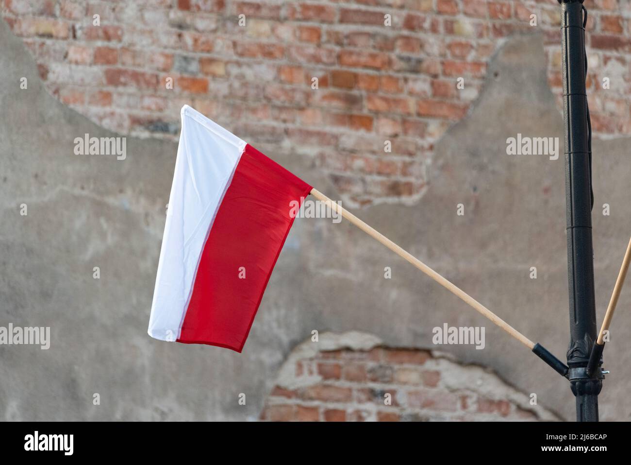 A small Polish flag on a blurry background of bricks with peeling ...