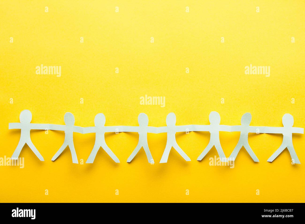 Light blue paper people on yellow background. Friendship flatlay ...