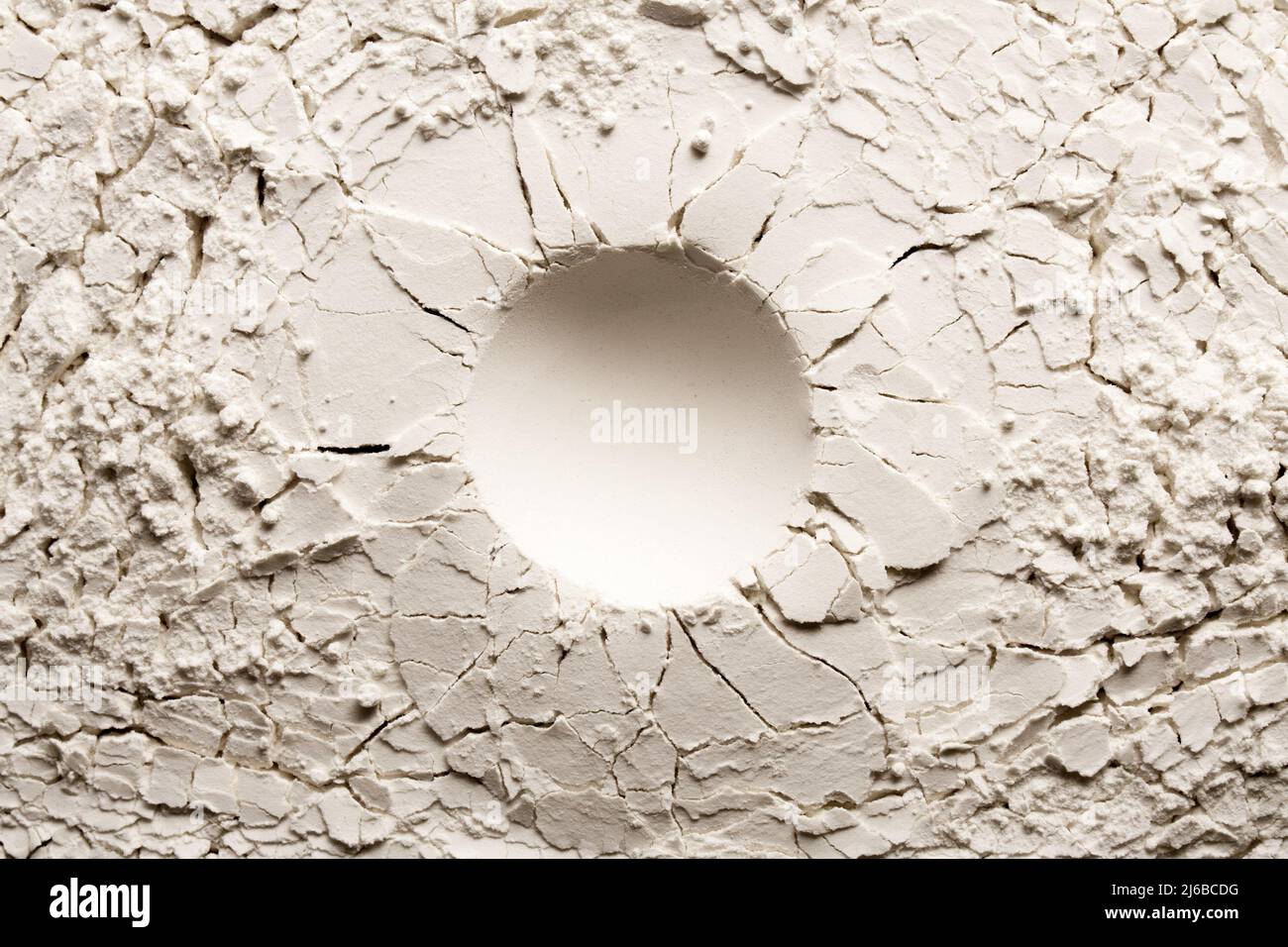 Round crater on white backgroung with crack. Cracked background with a ...