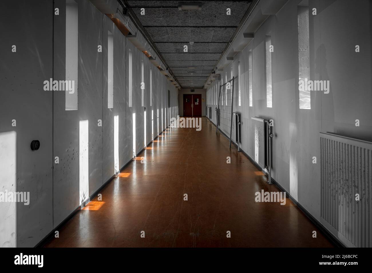 A long bare corridor with light and dark shadow spots. The corridor ...
