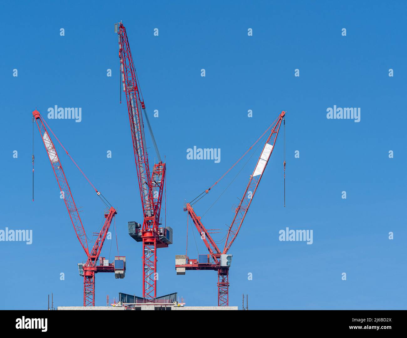 Multiple tower cranes above a concrete structure. The cranes consist of ...
