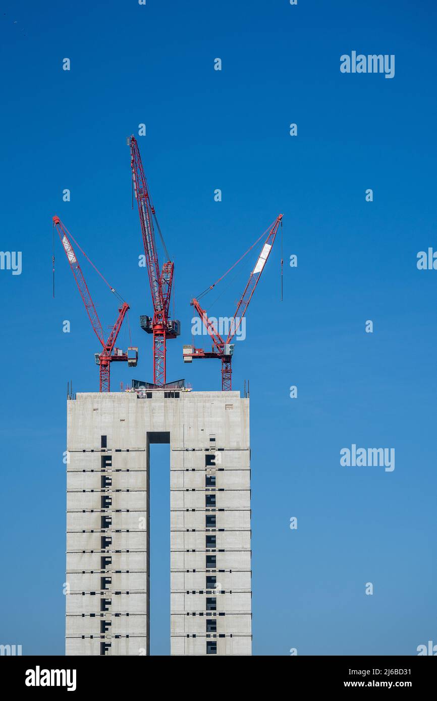 Multiple tower cranes above a concrete structure. The cranes consist of ...