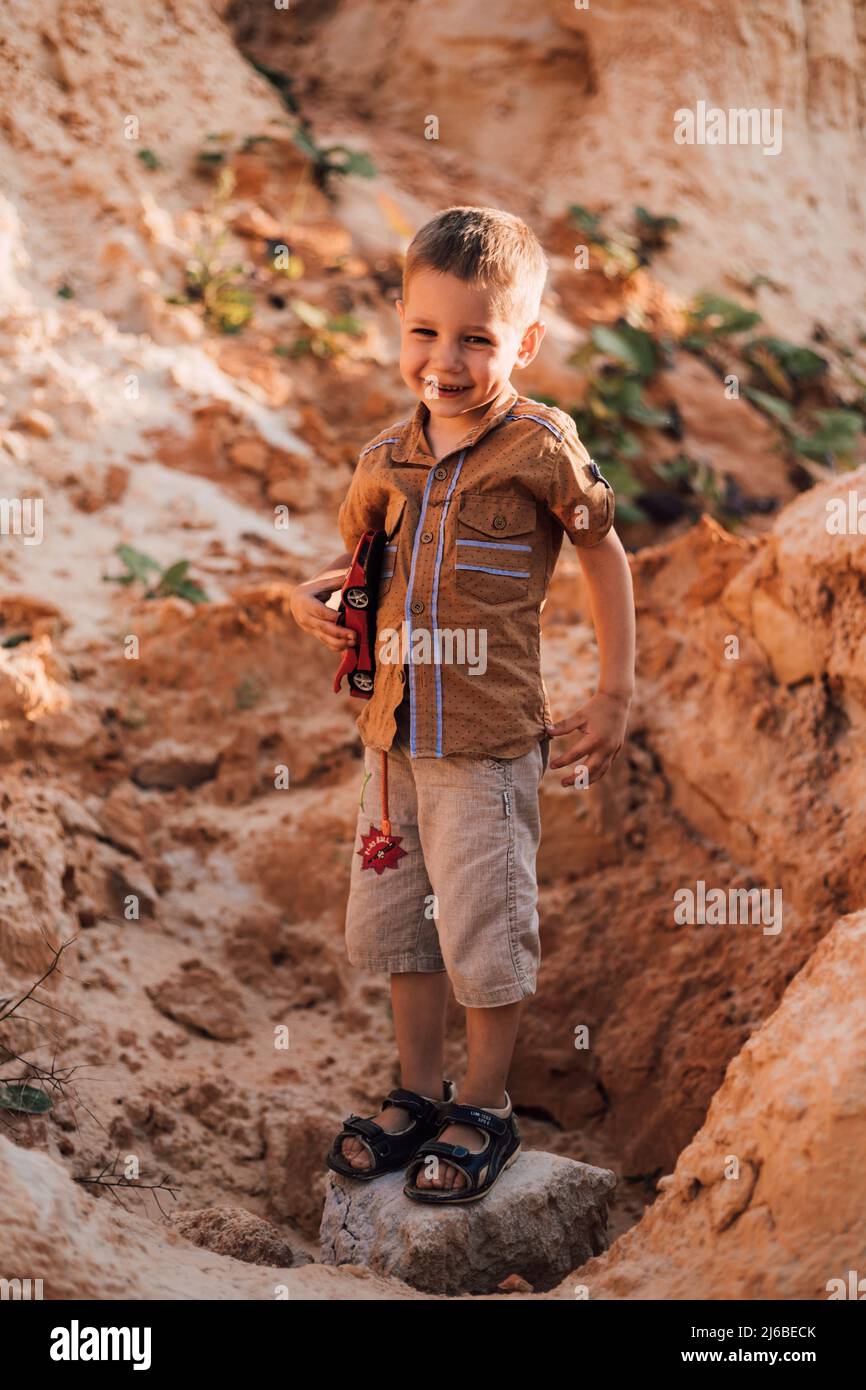A small child boy stands on a rock among the sand Stock Photo - Alamy