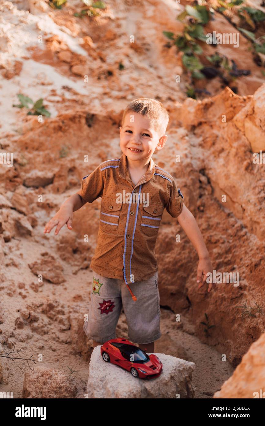 A small child boy stands on a rock among the sand Stock Photo - Alamy