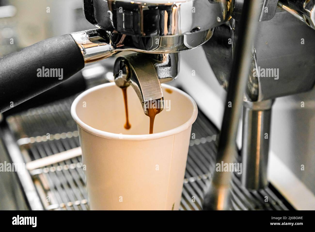 Professional coffee making machine pouring a take out drink at local ...