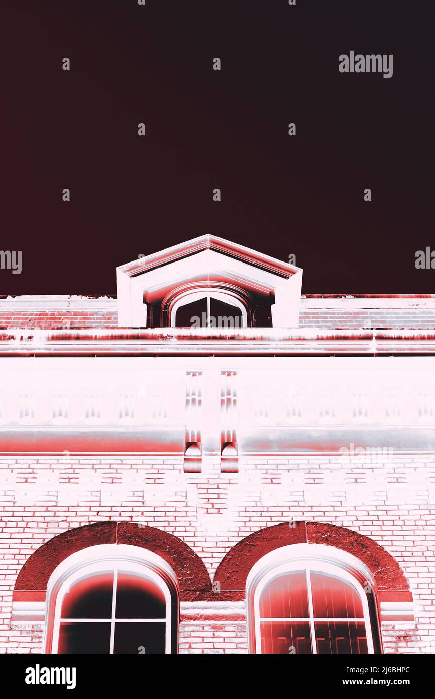 A traditional colonial attic window high on the roofline in pink high ...