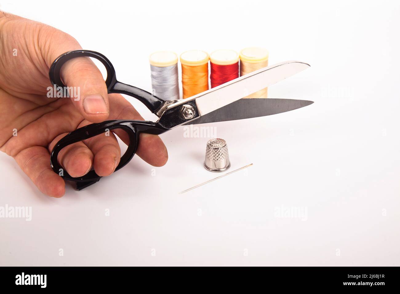 Sewing supplies concept, hand tailor scissors colorful threads needle ...