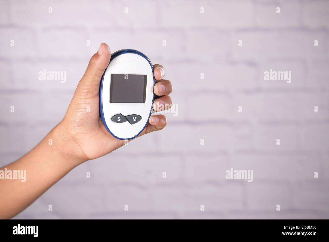 holding a Blood Glucometer against white wall Stock Photo - Alamy