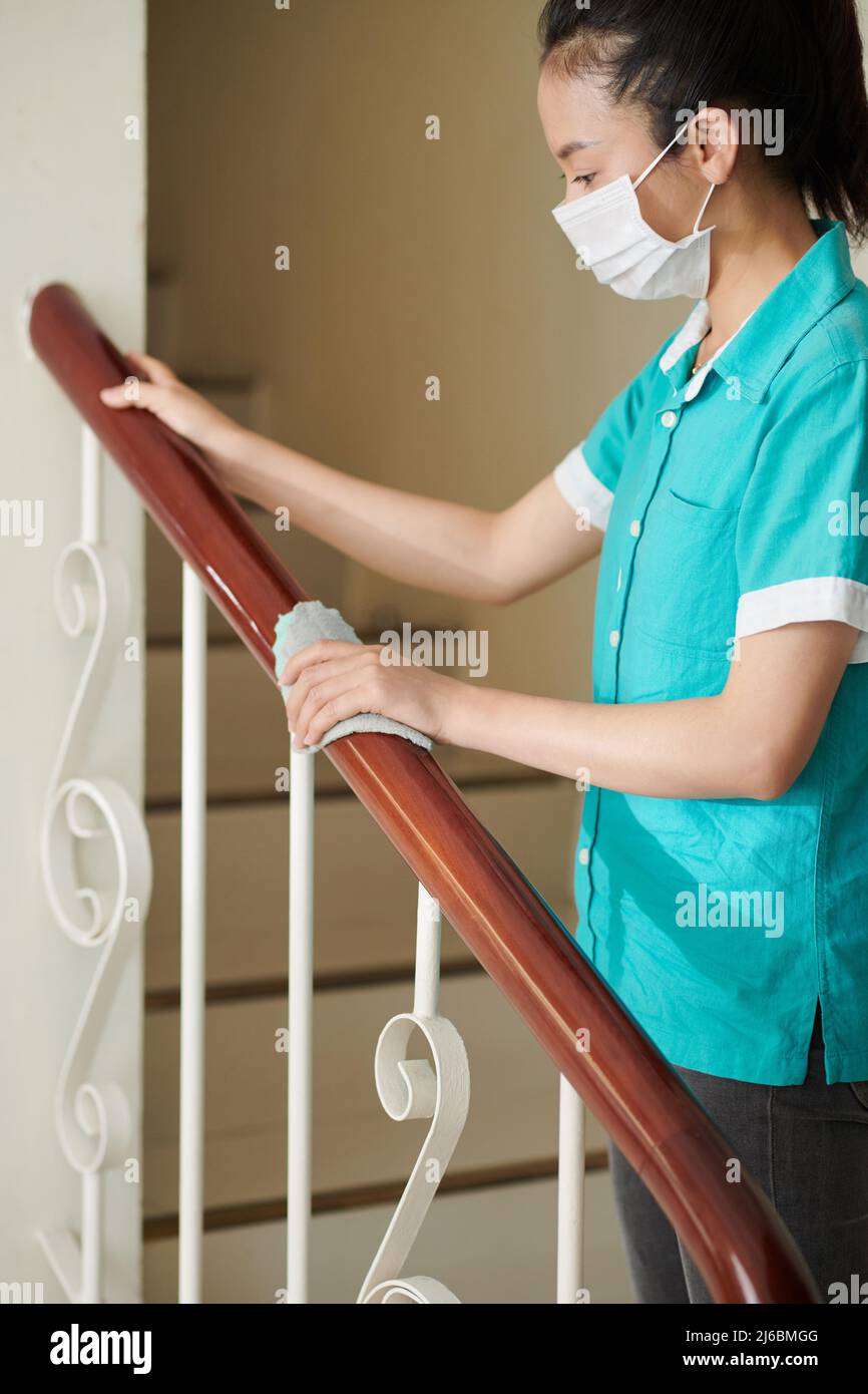 Professional cleaner in uniform and medical mask cleaning wooden ...