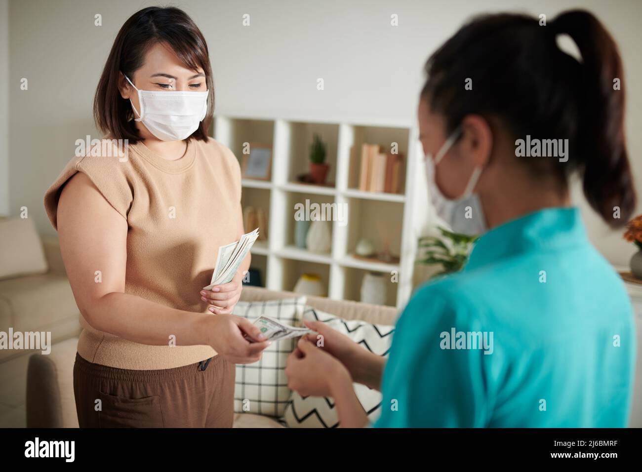Woman giving tips to maid after she cleaned whole house Stock Photo - Alamy