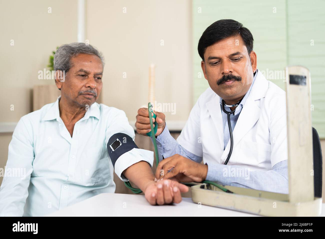 doctor checking blood pressure of elderly patient at hospital - concept ...