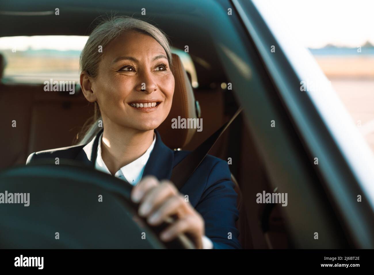 Mature asian businesswoman with grey hair smiling while driving car Stock Photo - Alamy