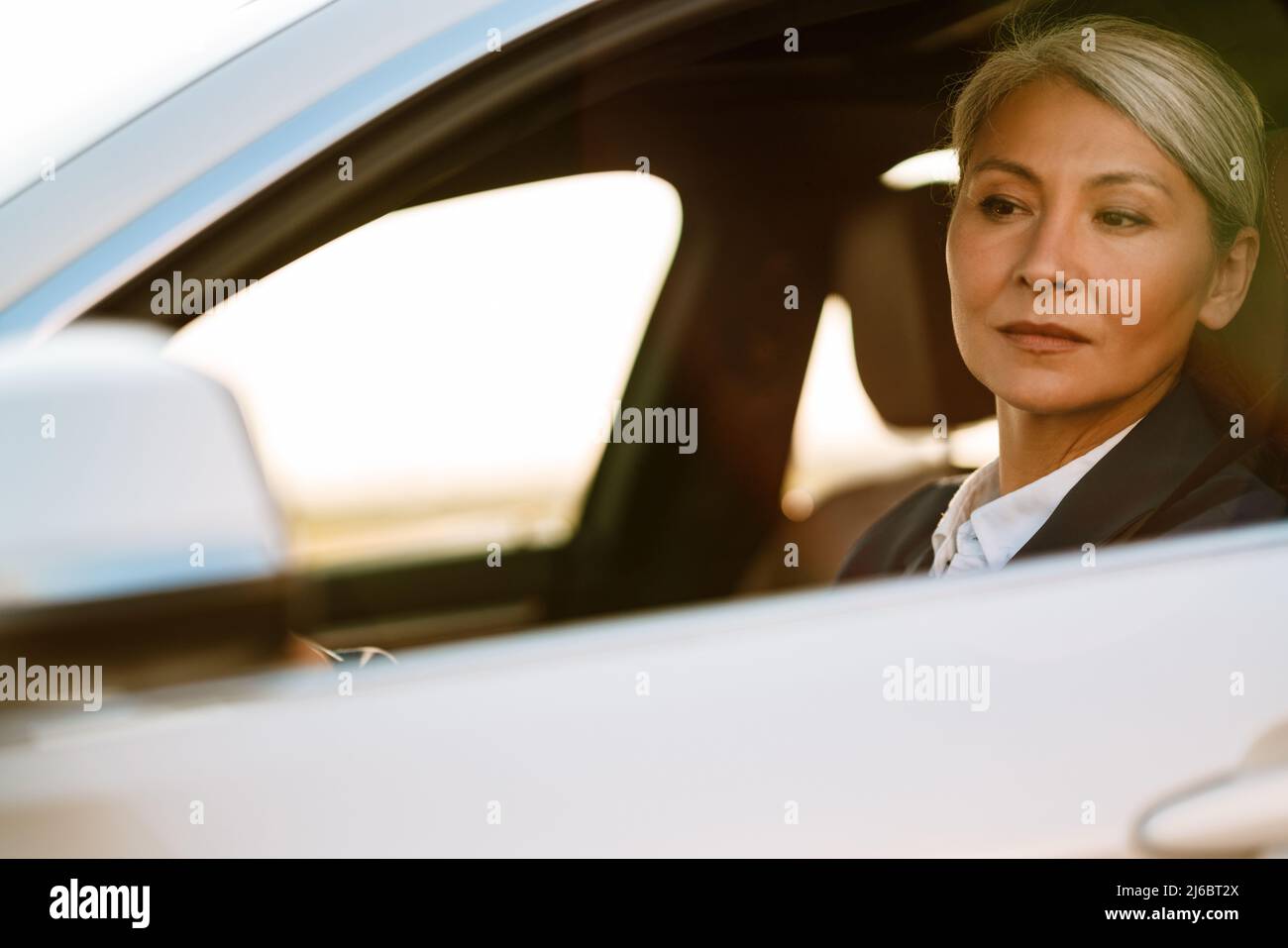 Mature asian businesswoman with grey hair driving car Stock Photo - Alamy