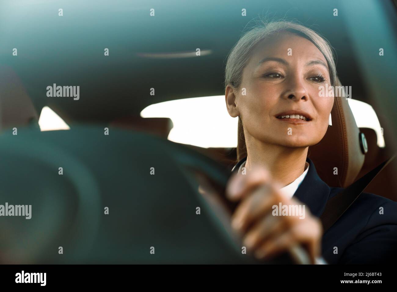 Mature asian woman with grey hair using earphone while driving car Stock Photo - Alamy