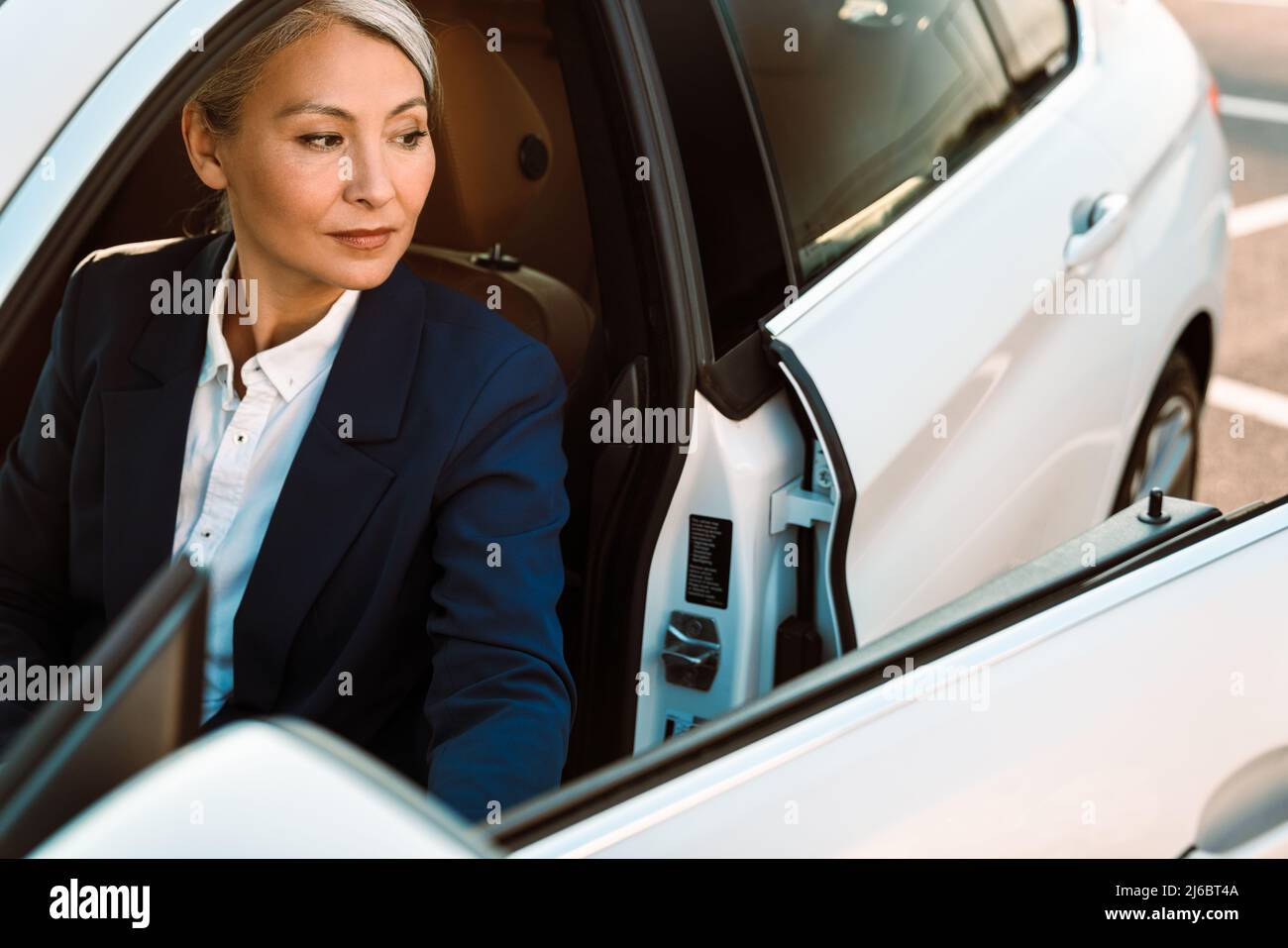Mature asian businesswoman with grey hair getting out car Stock Photo - Alamy