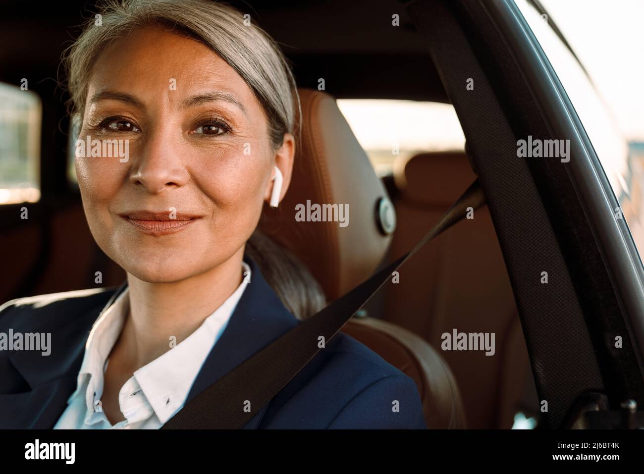 Mature asian woman with grey hair using earphone while driving car Stock Photo - Alamy