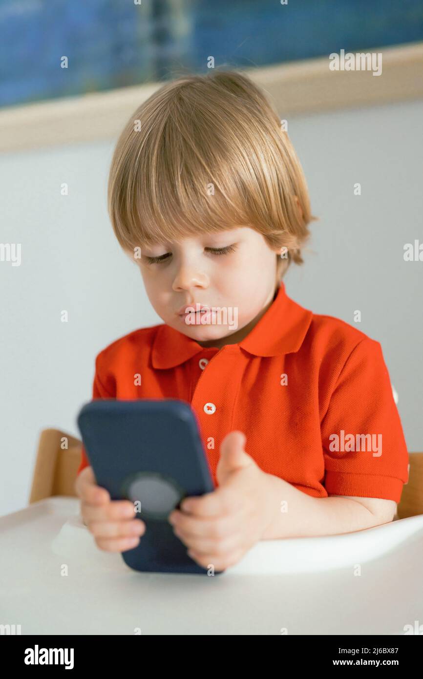 Close up cute little boy using smartphone, looking at screen, curious ...