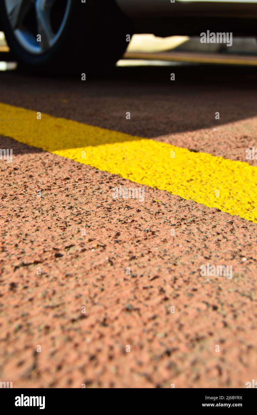 Red asphalt concrete road with yellow stripes and car parking area ...