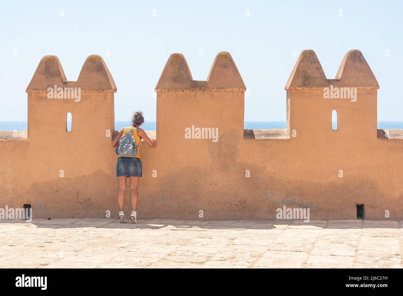 Anonymous female traveler near aged towers near sea Stock Photo - Alamy