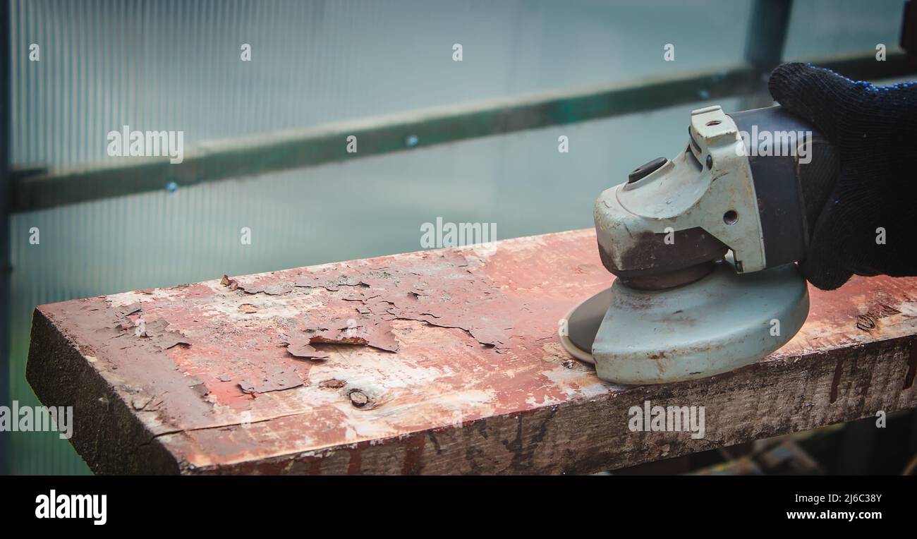 a man is grinding a board. Removing old paint from boards. Carpentry ...