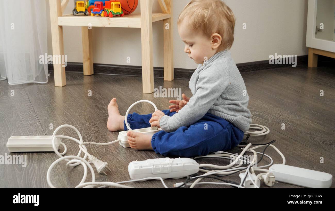 Little baby boy playing with electric cables and wires. CHild in danger ...