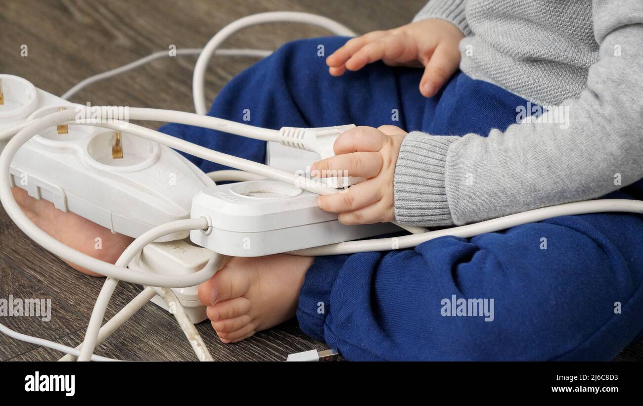 Closeup of little baby boy inserting electric plug. CHild playing with ...