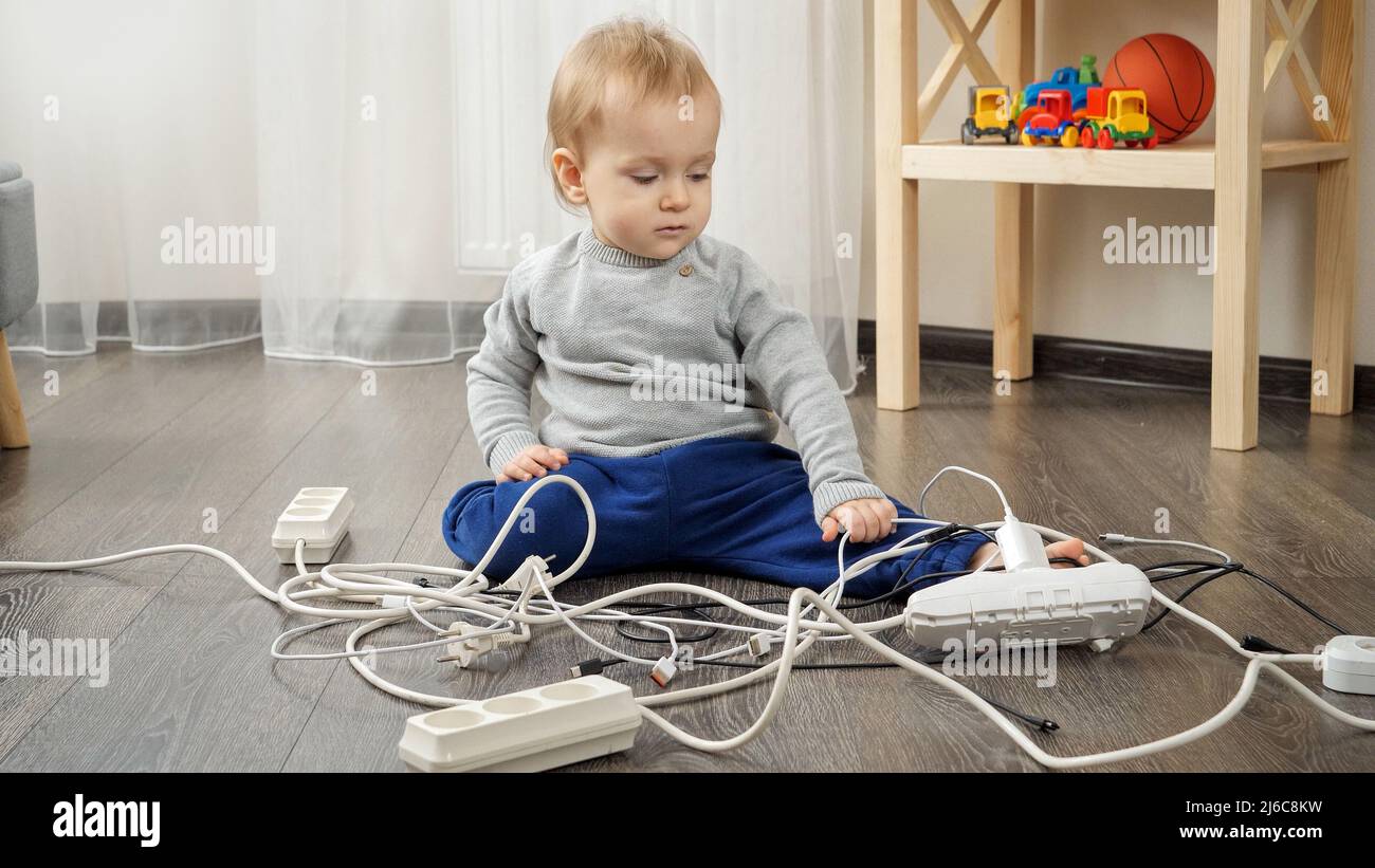 Little baby boy left alone playing with electric cables and wires ...