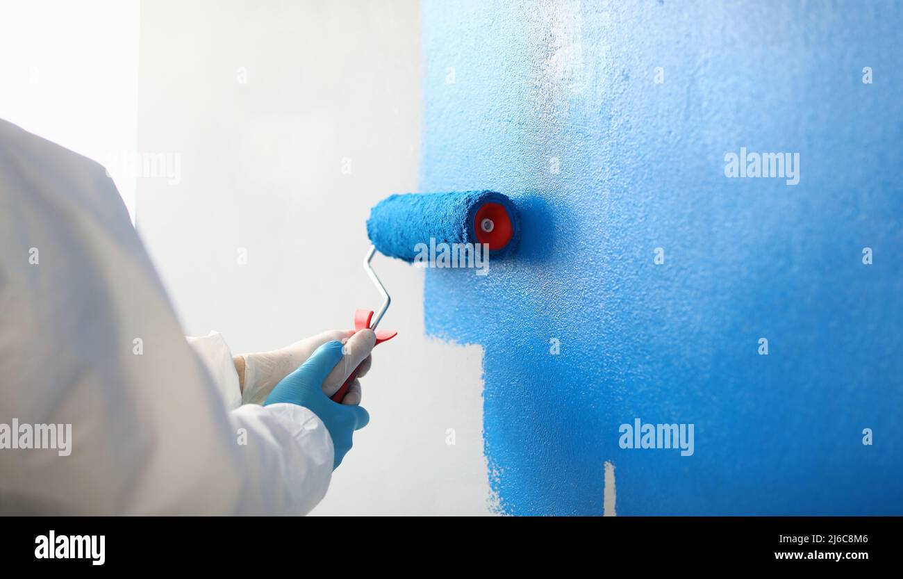 Painter with brush tool covered in blue colour painting wall Stock ...