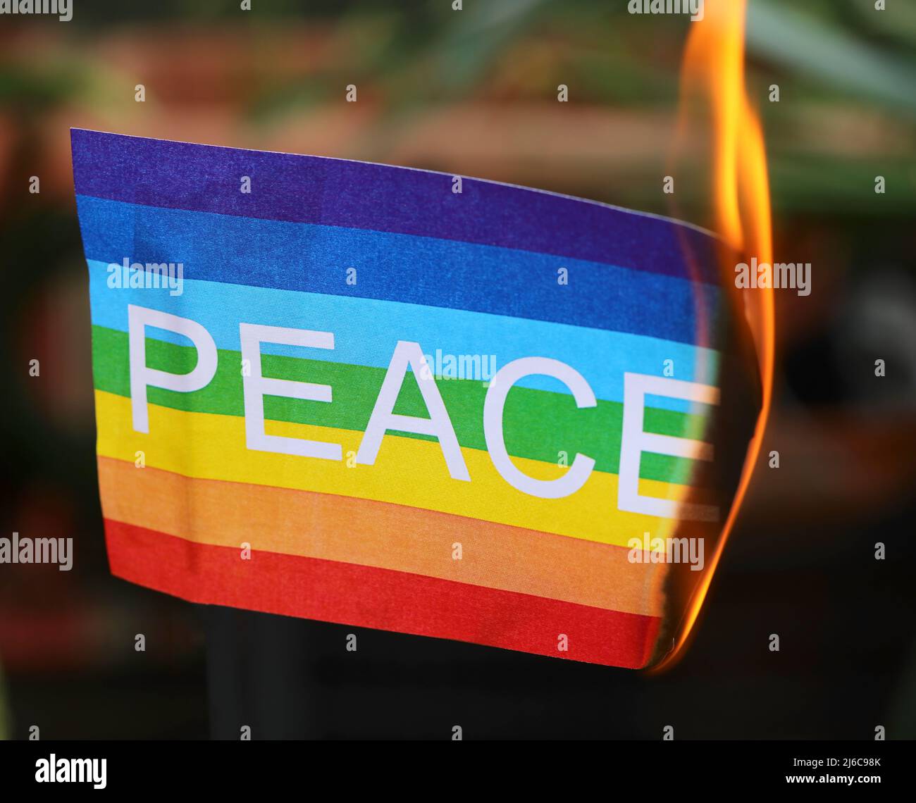 peace flag with the colors of the rainbow and the text while burning ...