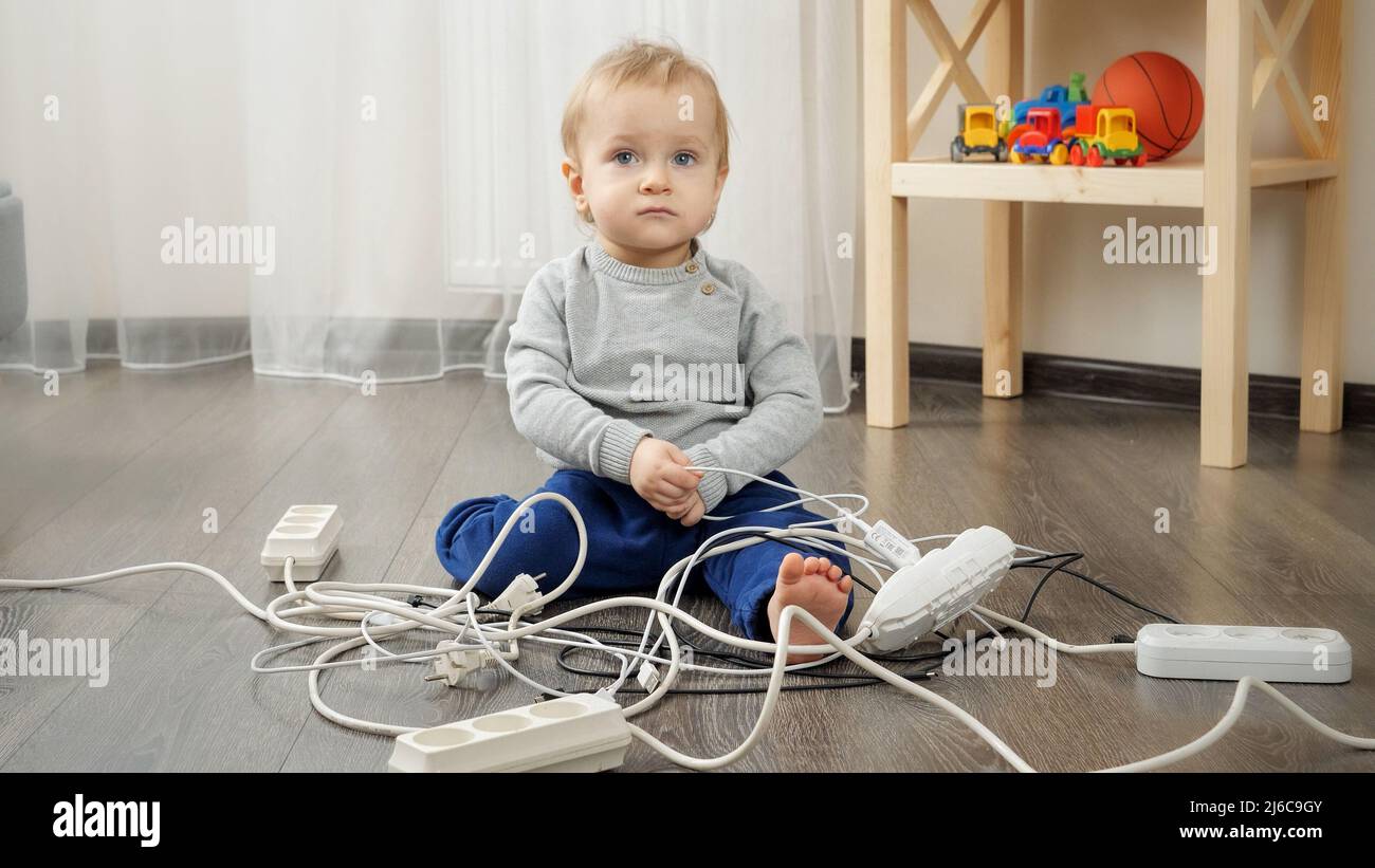 Little baby boy playing with electric plugs and wires at home Stock ...