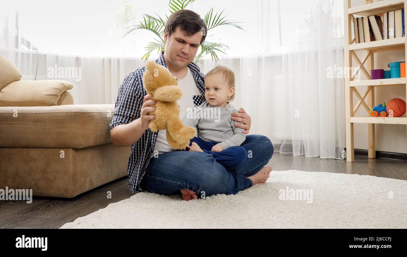 Happy smiling baby boy with father having fun and playing with teddy ...