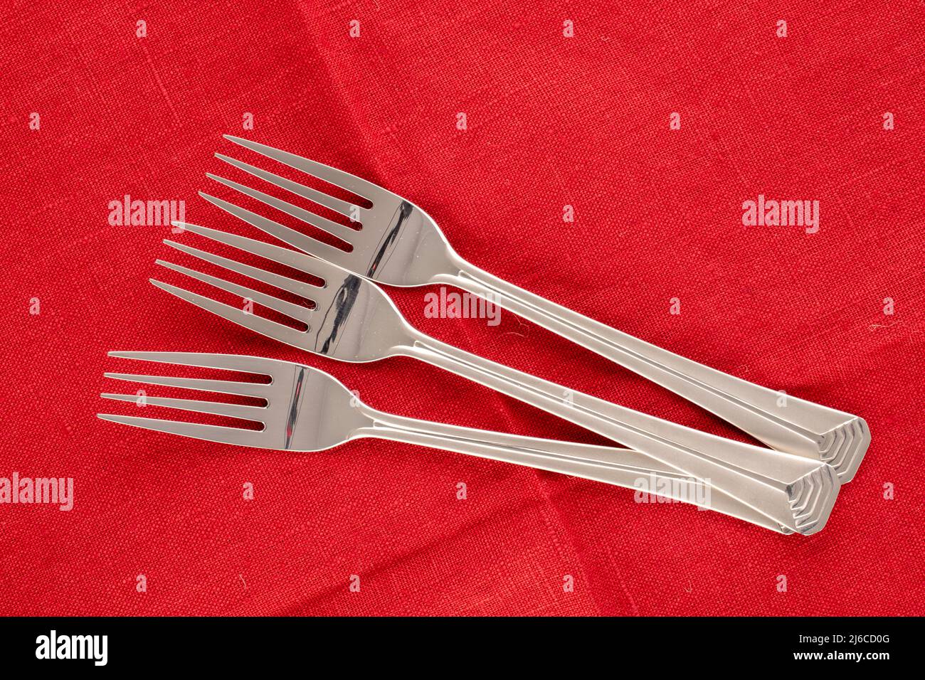 Three metal forks on a red linen napkin, macro, top view Stock Photo ...