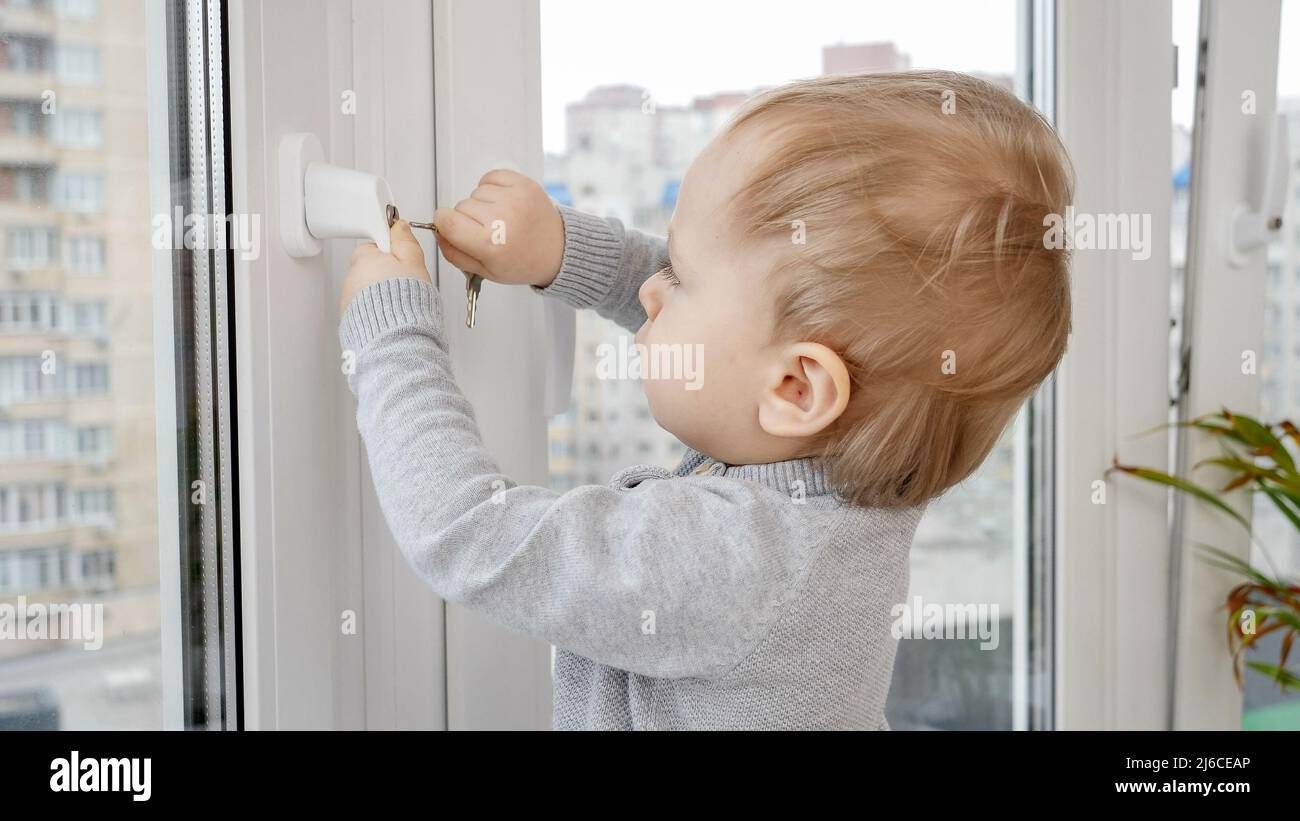 Little baby boy opens window safety lock with key. Baby in danger ...