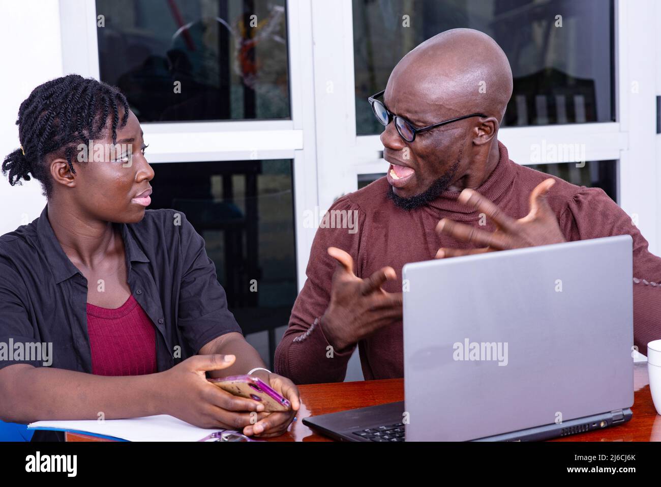 Businessman and woman sitting at table in meeting room with open laptop ...