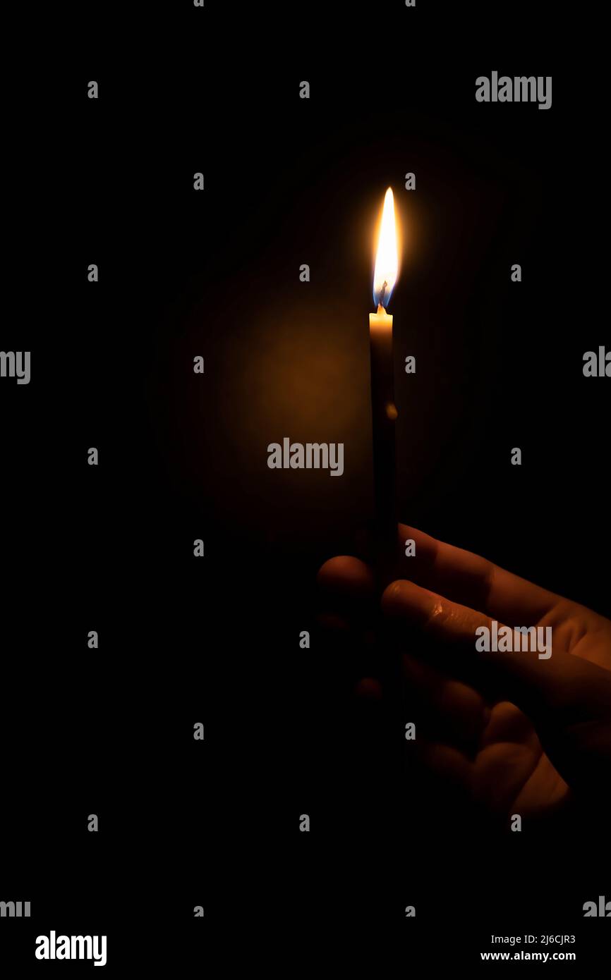 Candle in hand. Female hand holding a burning candle. On a black ...