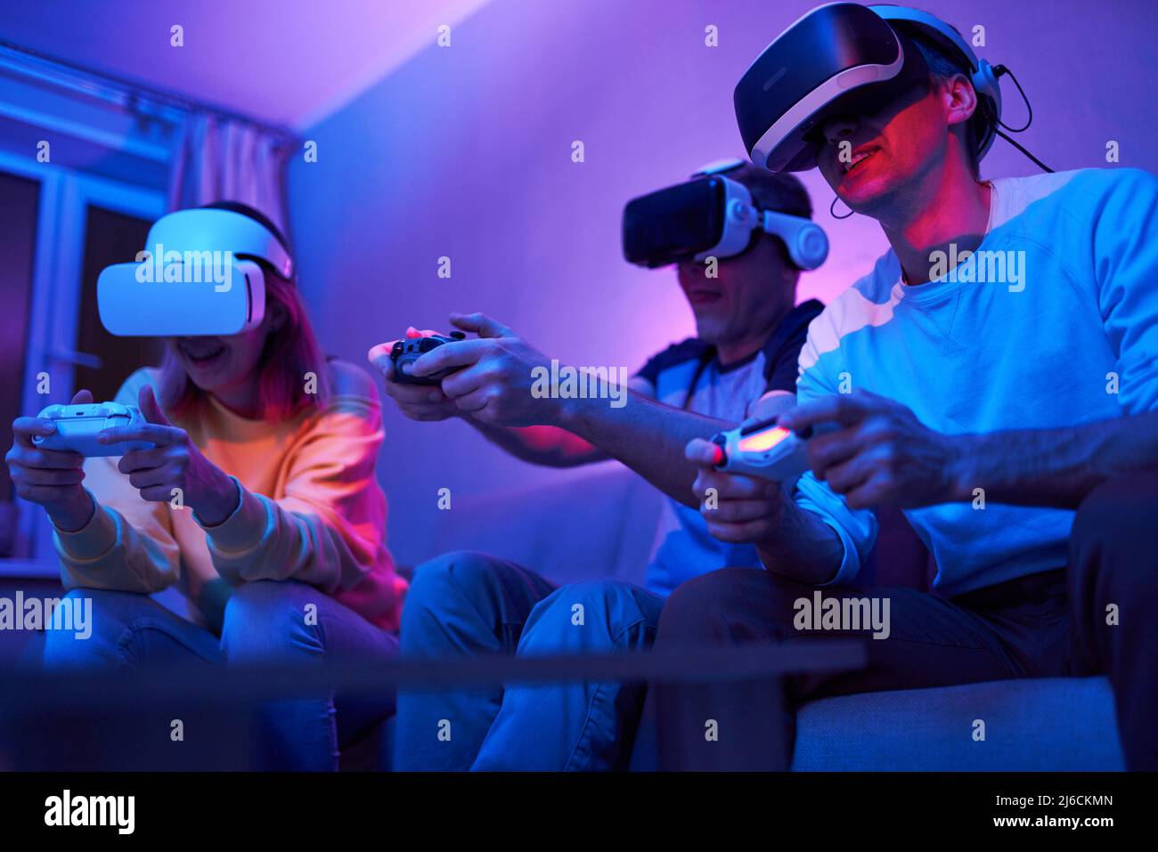 Friends playing virtual reality games using joysticks while sitting on ...