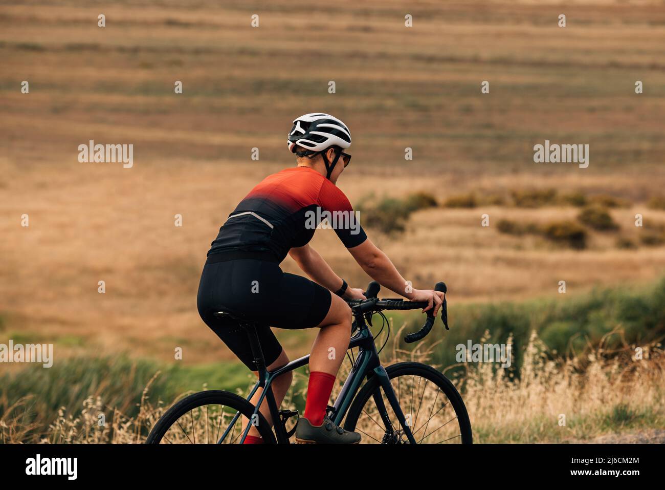 Back view of female cyclist on a country road training for competition ...